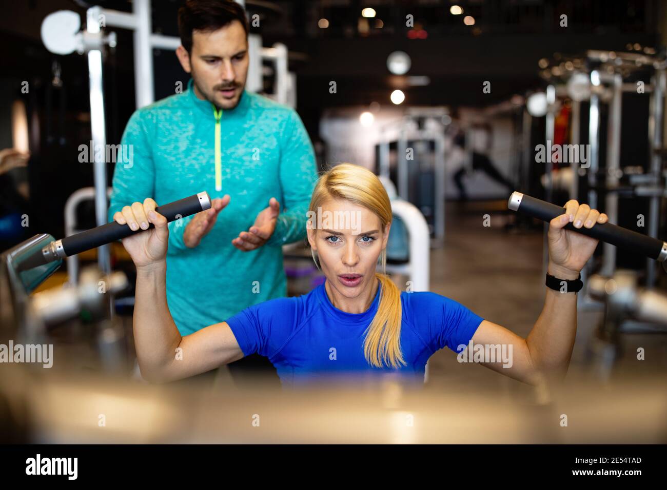 Beautiful woman doing exercises in gym with personal trainer Stock ...