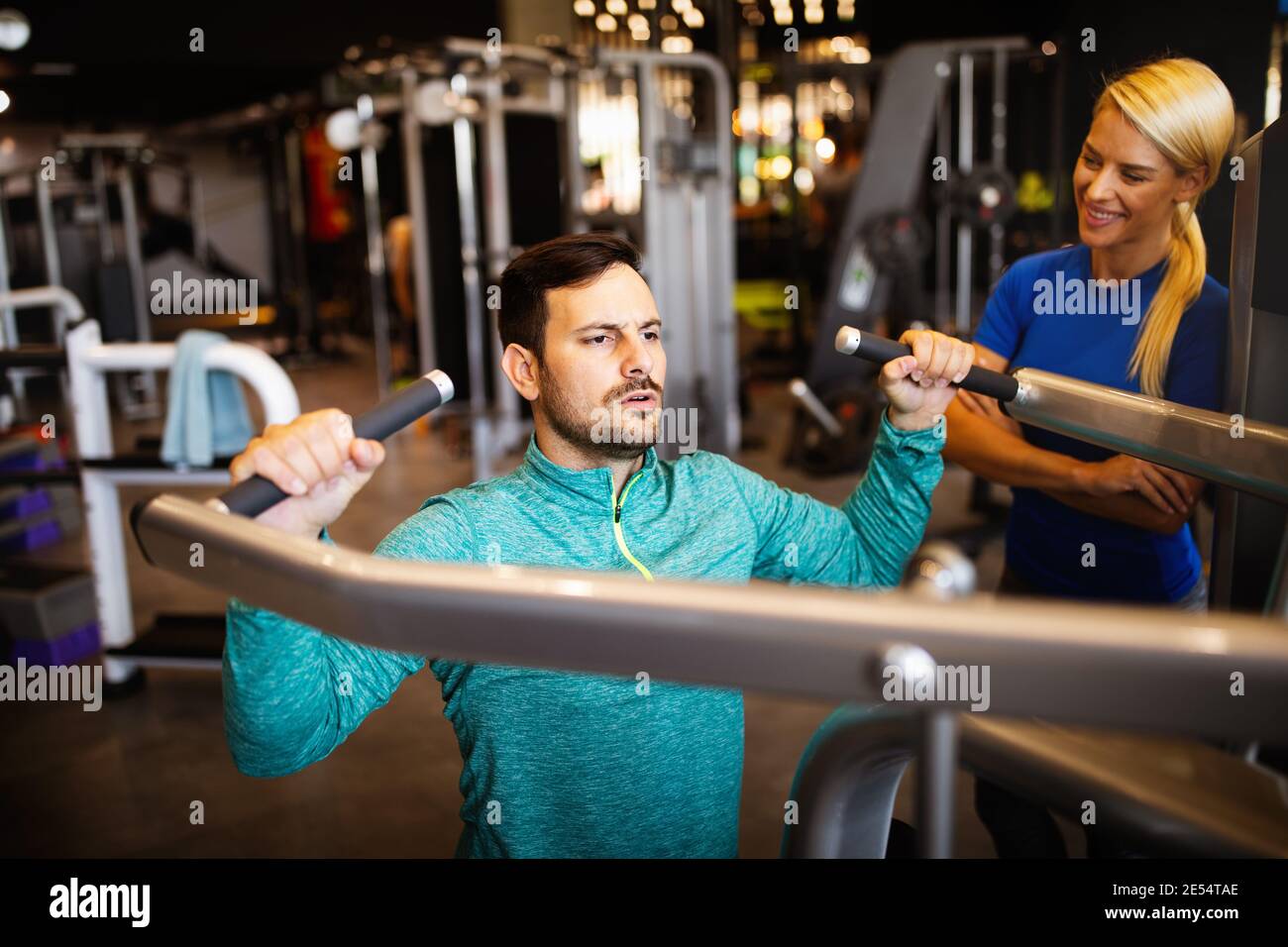 Fit happy man exercising at the gym on a machine Stock Photo - Alamy