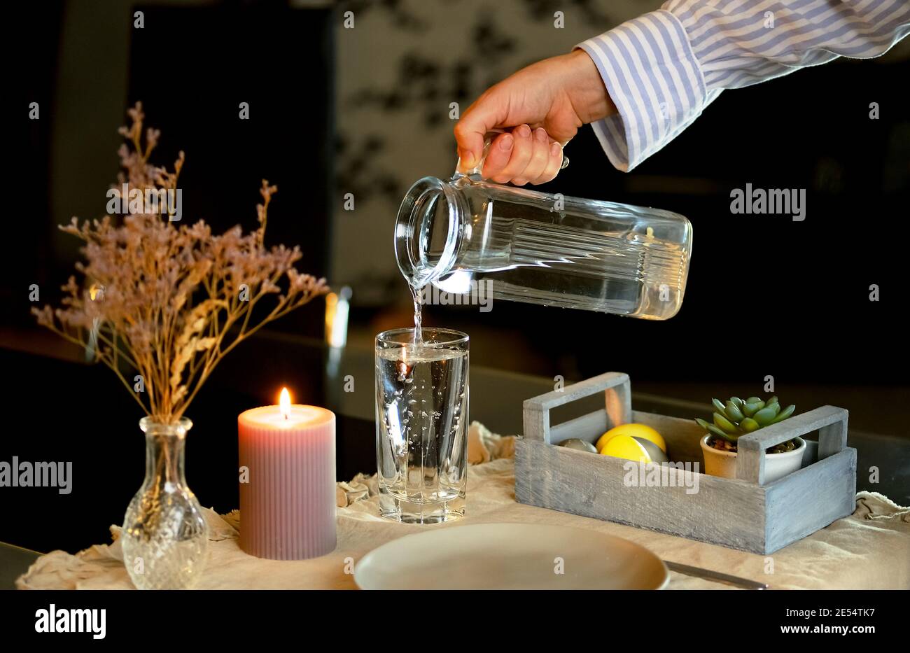 Woman setting table and pouring water for home dining. Celebrating ...