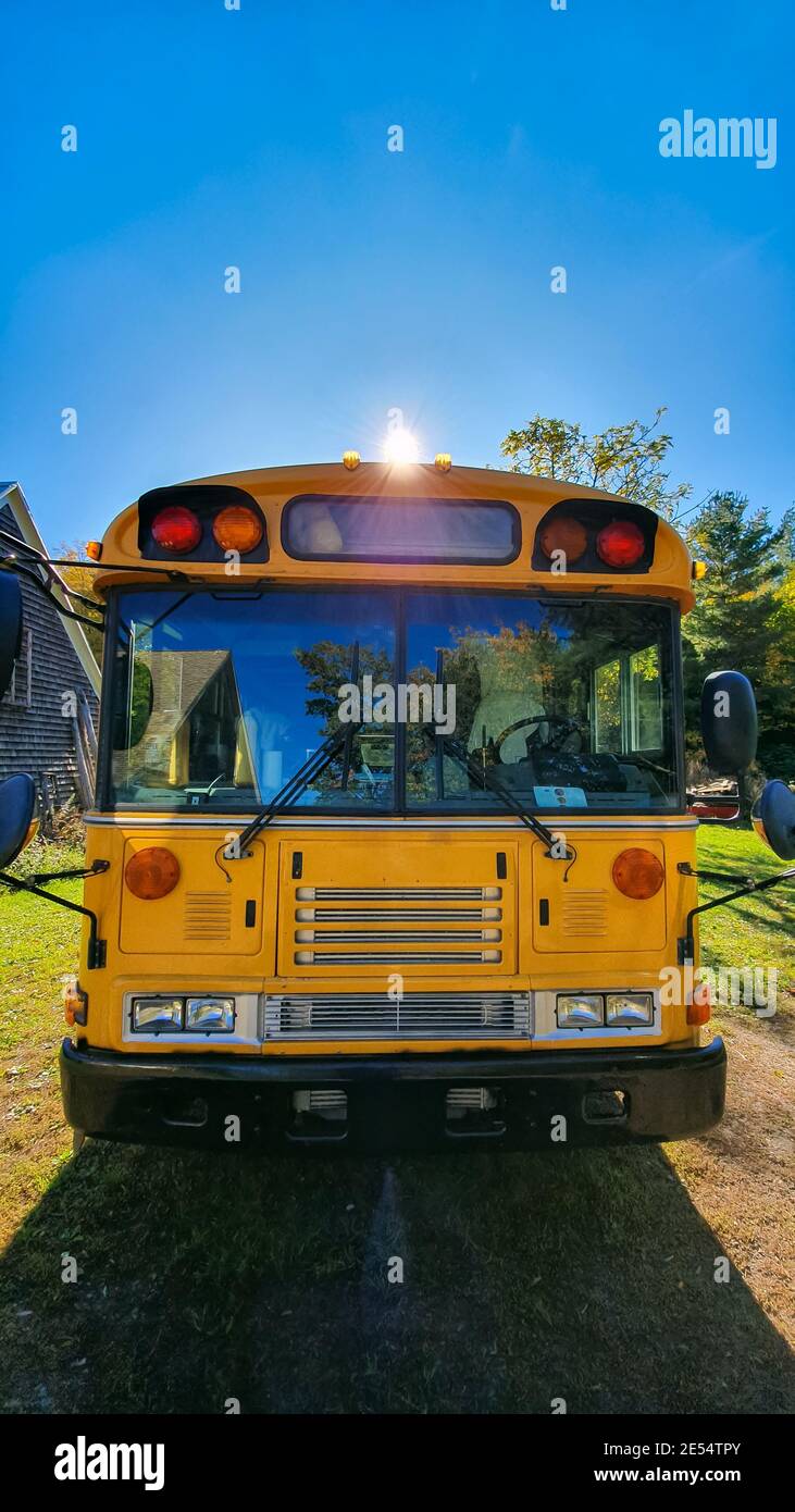 Frontal shot of the head of a vintage bright yellow bus parked in a ...