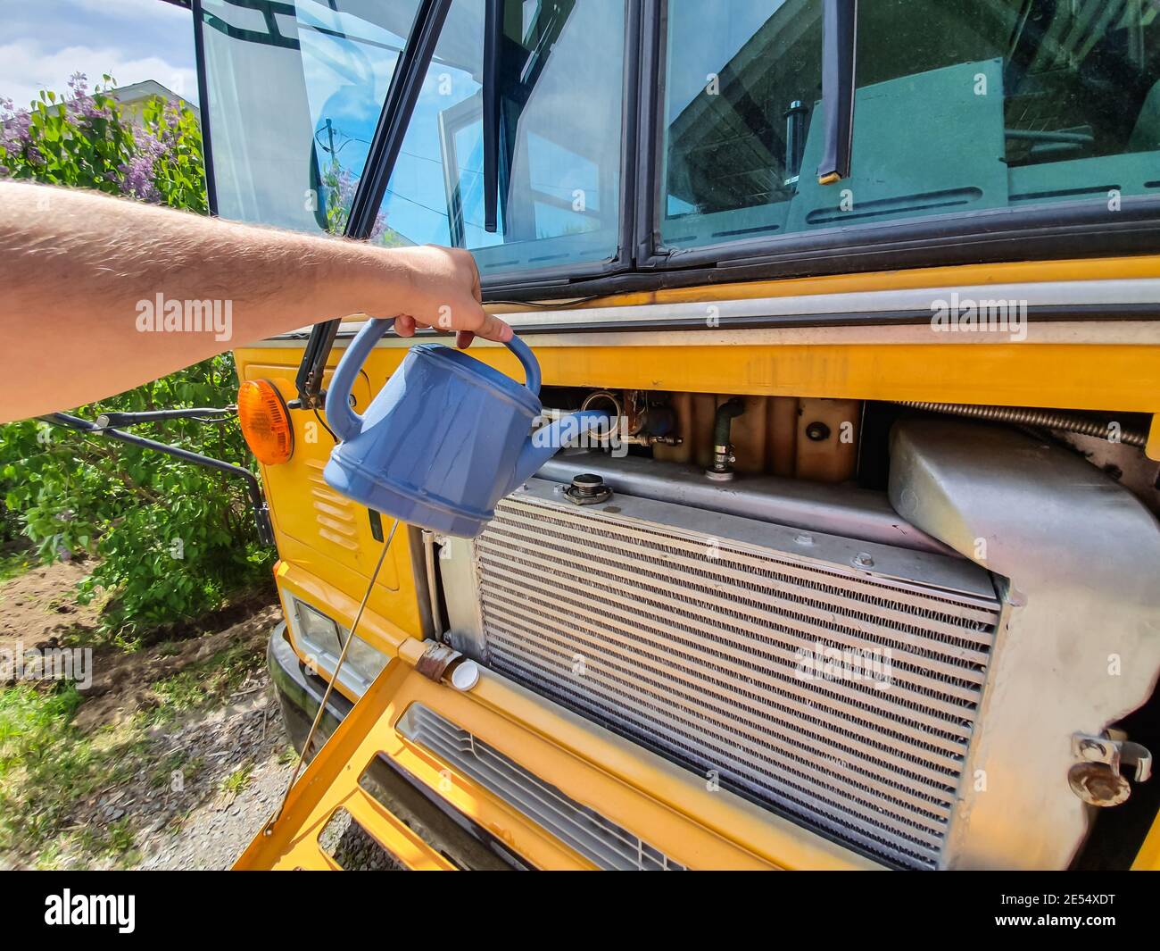 Close up shot of a man's hand pouring water with a blue watering can in ...