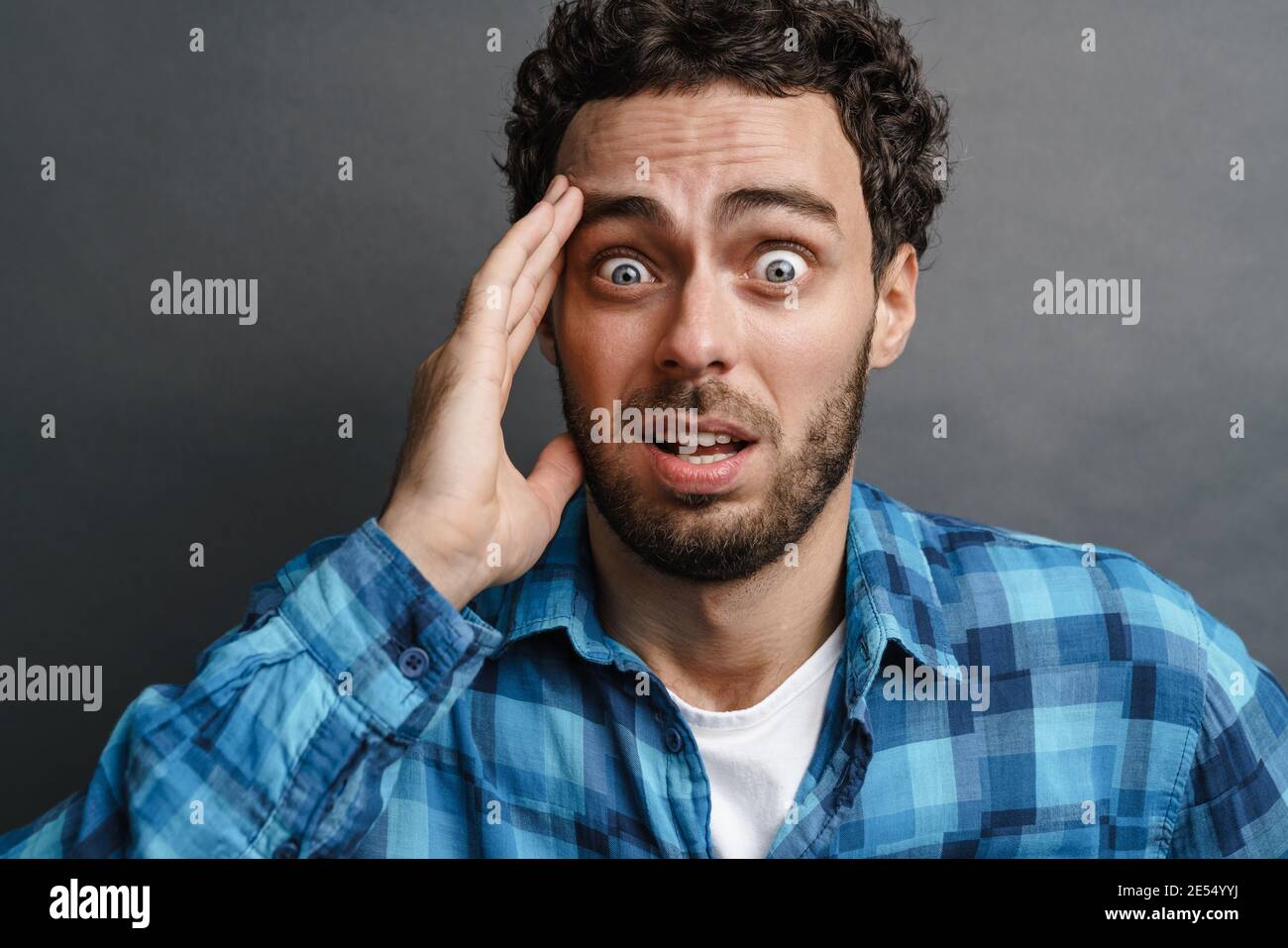 Shocked handsome guy expressing surprise on camera isolated over grey ...