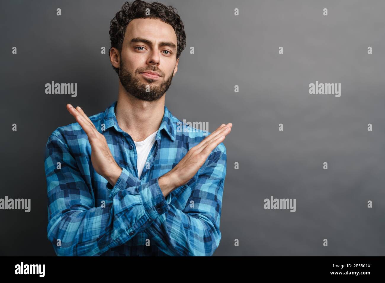 Unshaven tense guy showing stop gesture on camera isolated over grey ...
