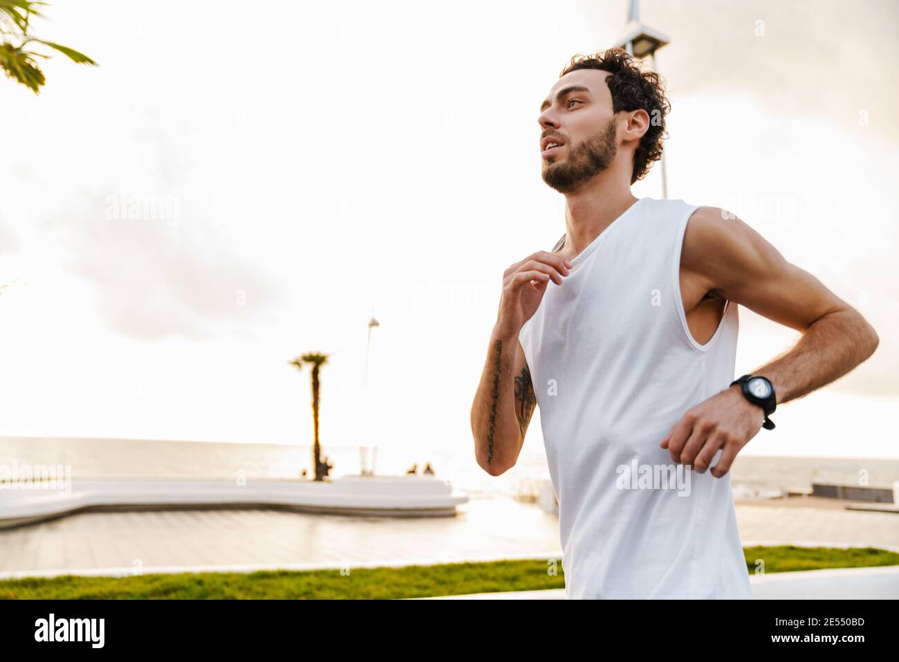 Focused unshaven guy running while working out on promenade Stock Photo ...