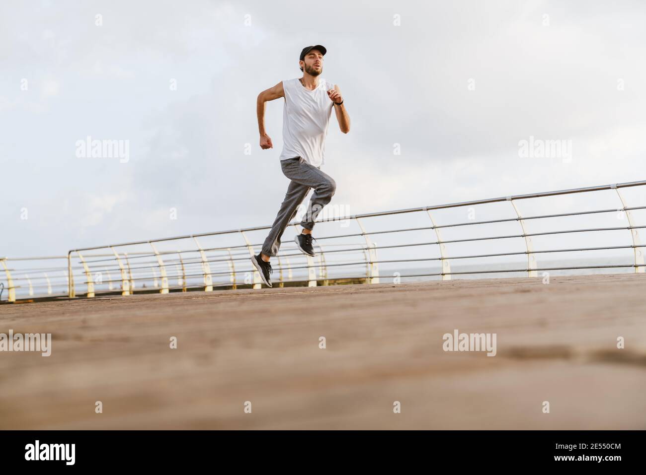 Focused unshaven guy running while working out on promenade Stock Photo ...