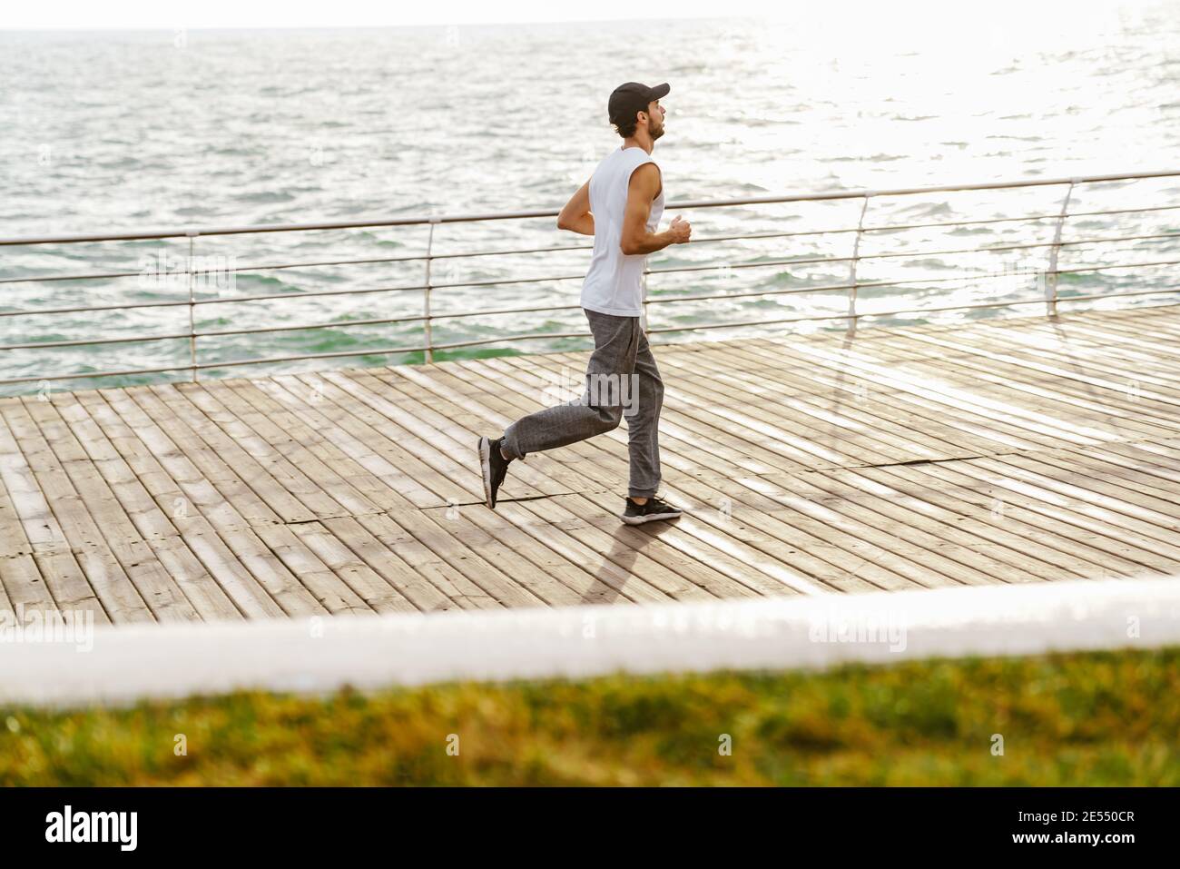 Focused unshaven guy running while working out on promenade Stock Photo ...
