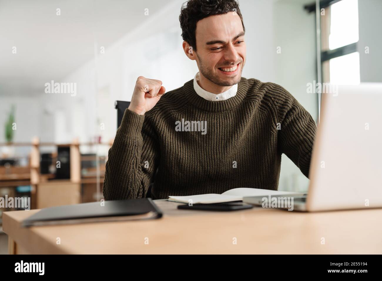 Smiling entrepreneur working with a laptop and documents in an office ...