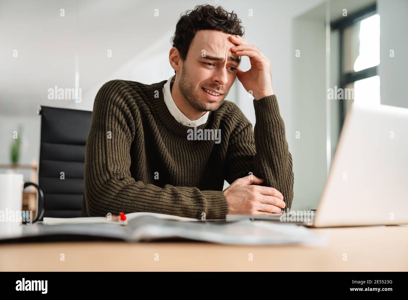 Stressed business man looking at laptop while sitting at the office ...