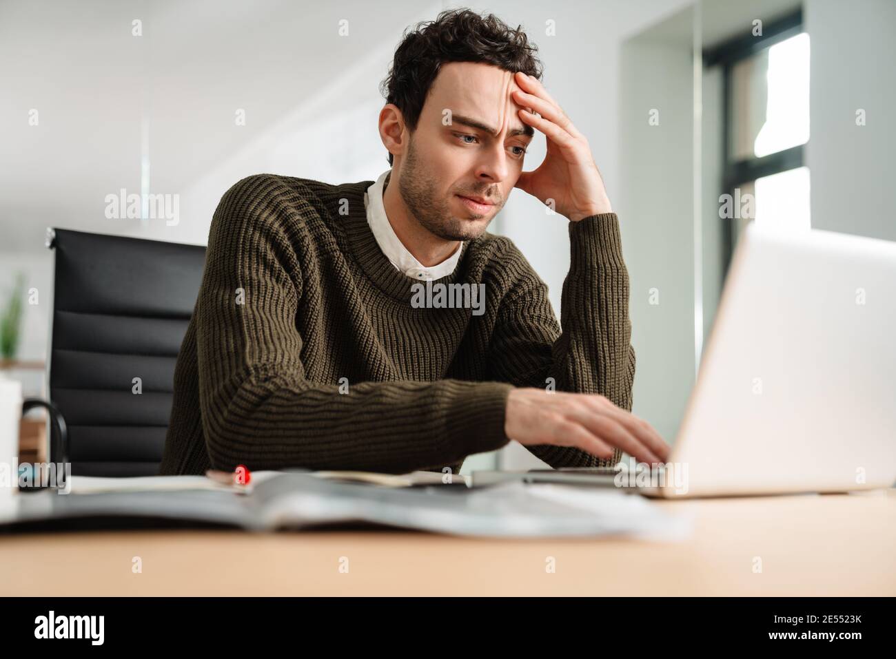 Stressed business man looking at laptop while sitting at the office ...
