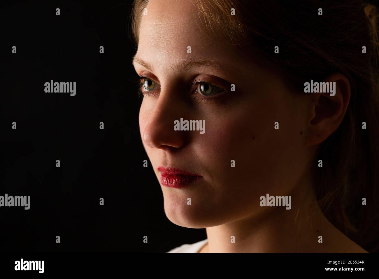 Unhappy woman looking without smile on black background Stock Photo - Alamy