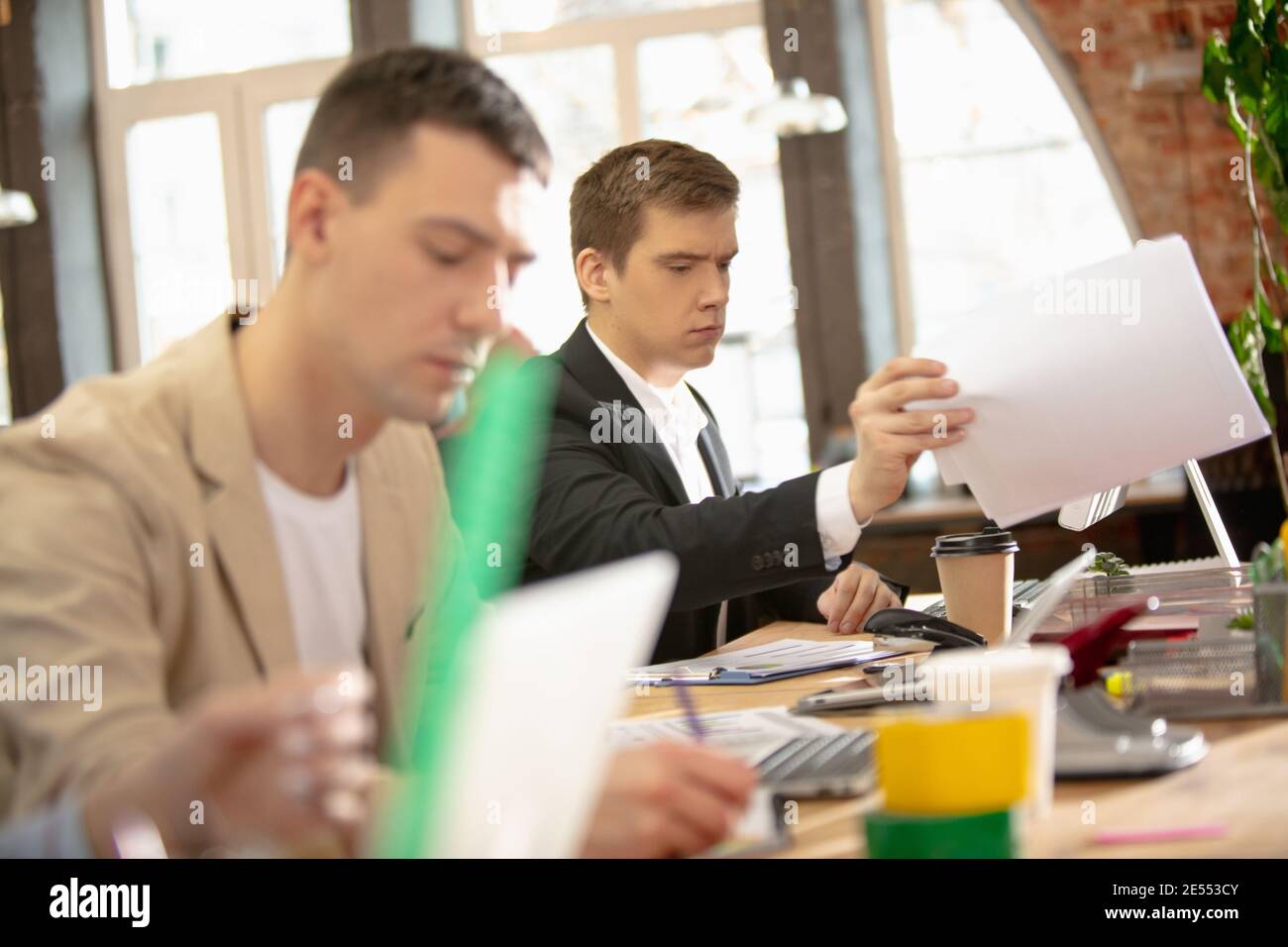 Preparing documents, contracts. Young caucasian colleagues working ...
