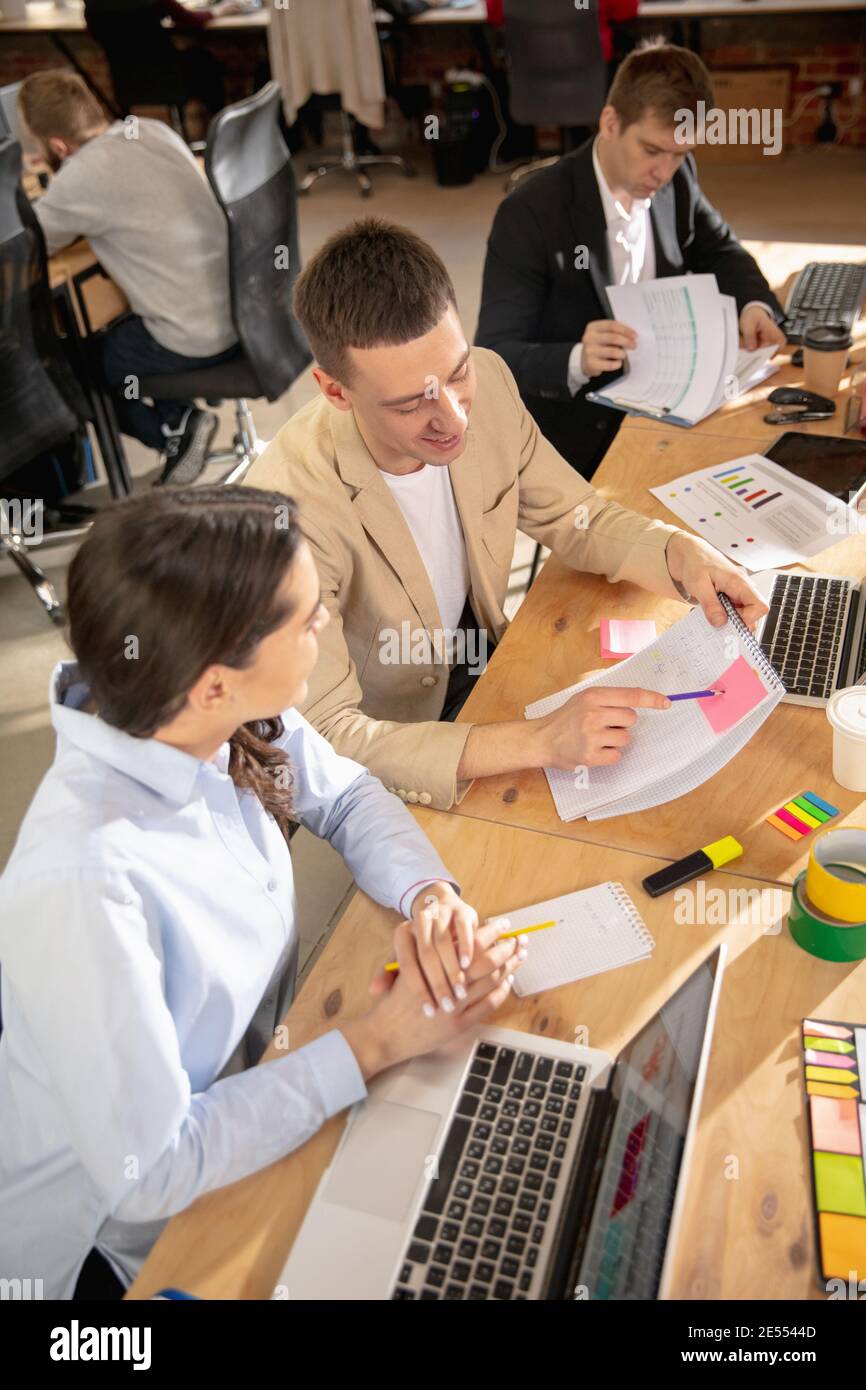 Writing notes, smiling. Young caucasian colleagues working together in ...