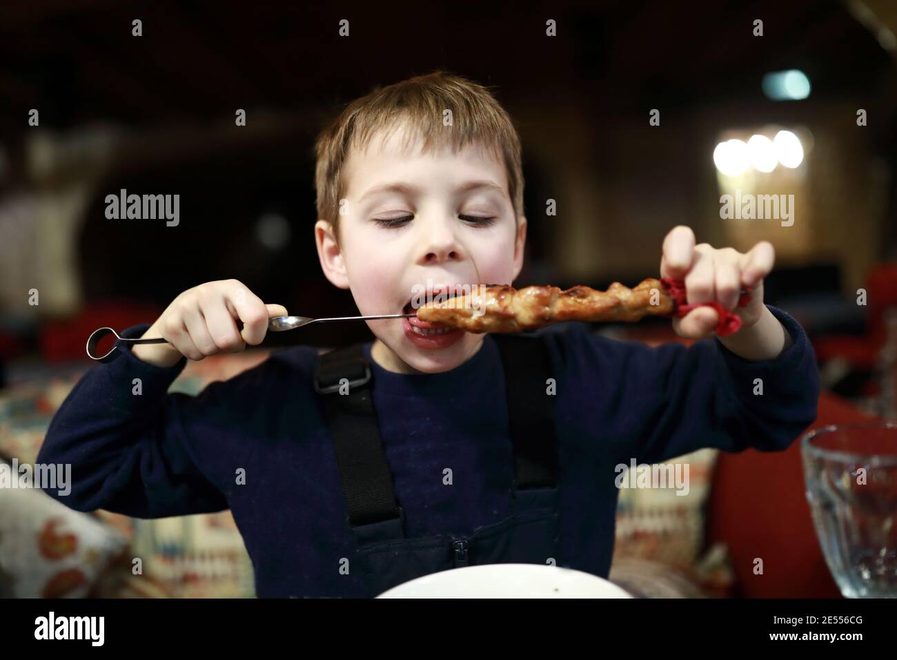 Portrait of kid eating kebab in restaurant Stock Photo - Alamy