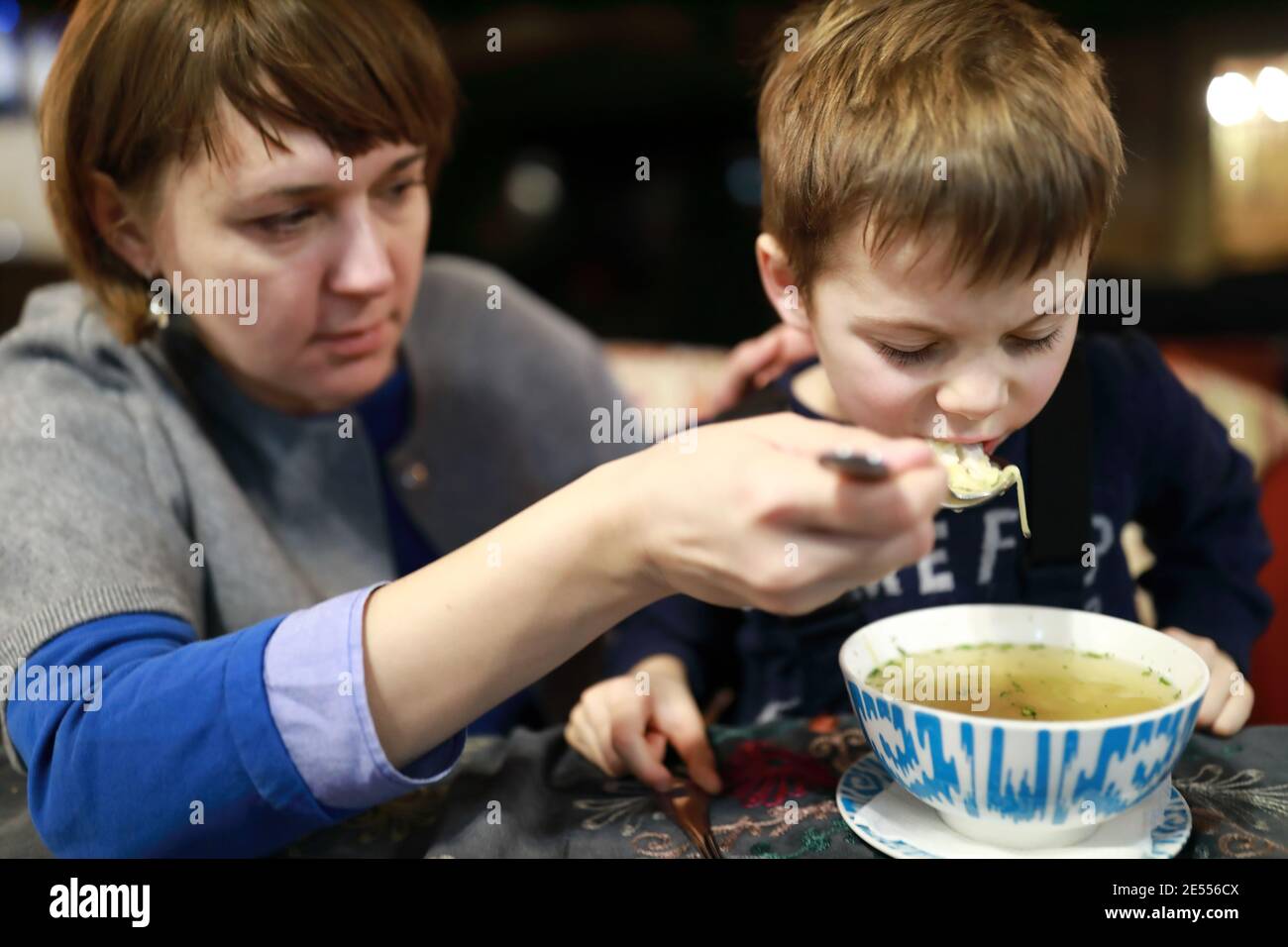 Mother feeding child with soup in restaurant Stock Photo - Alamy
