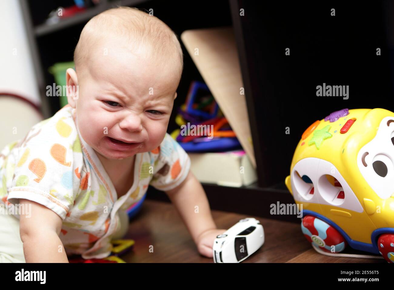 Crying baby sitting on a floor at home Stock Photo - Alamy