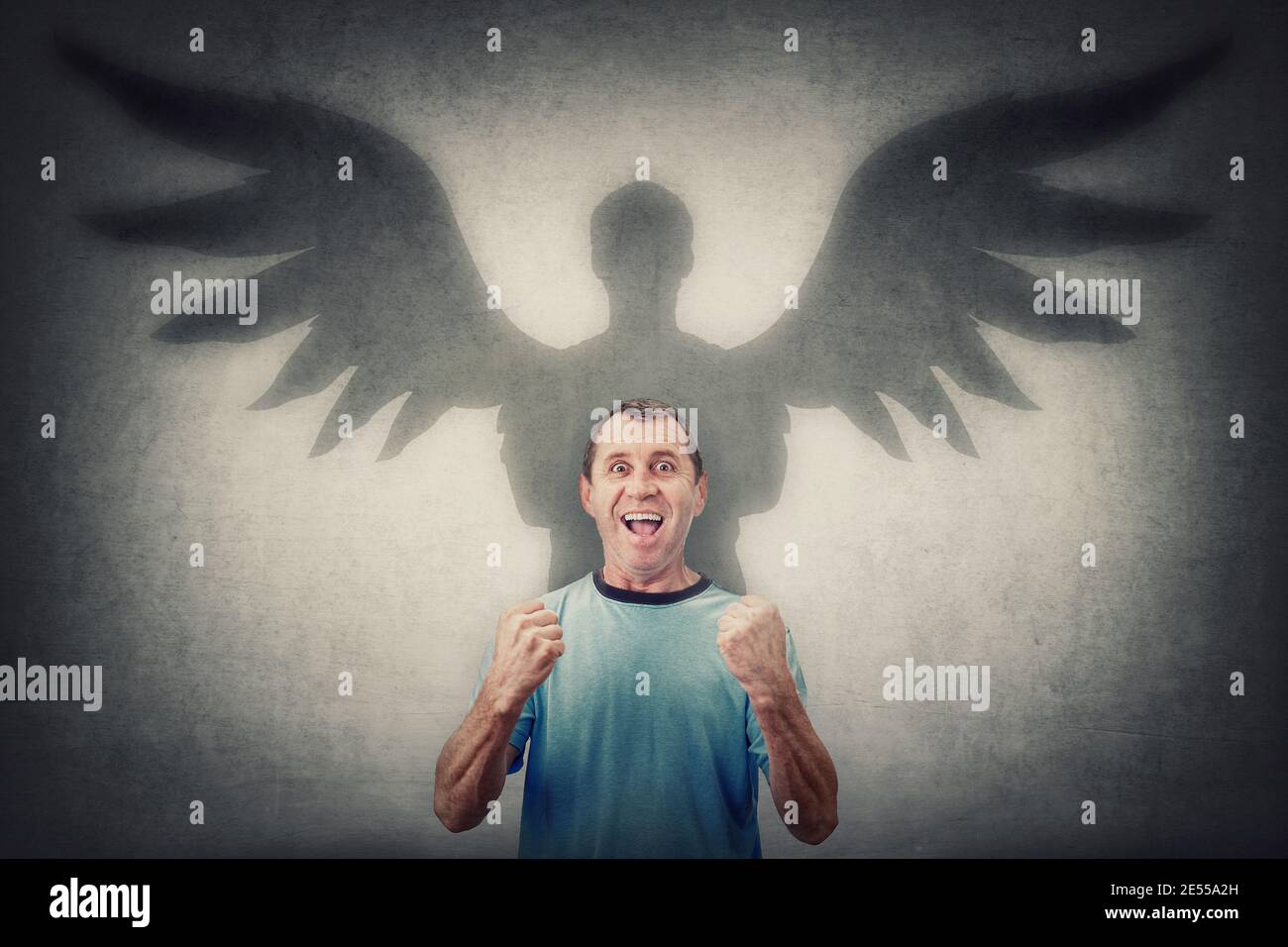 Courageous middle aged man keeps fists tight raised up, screaming ...