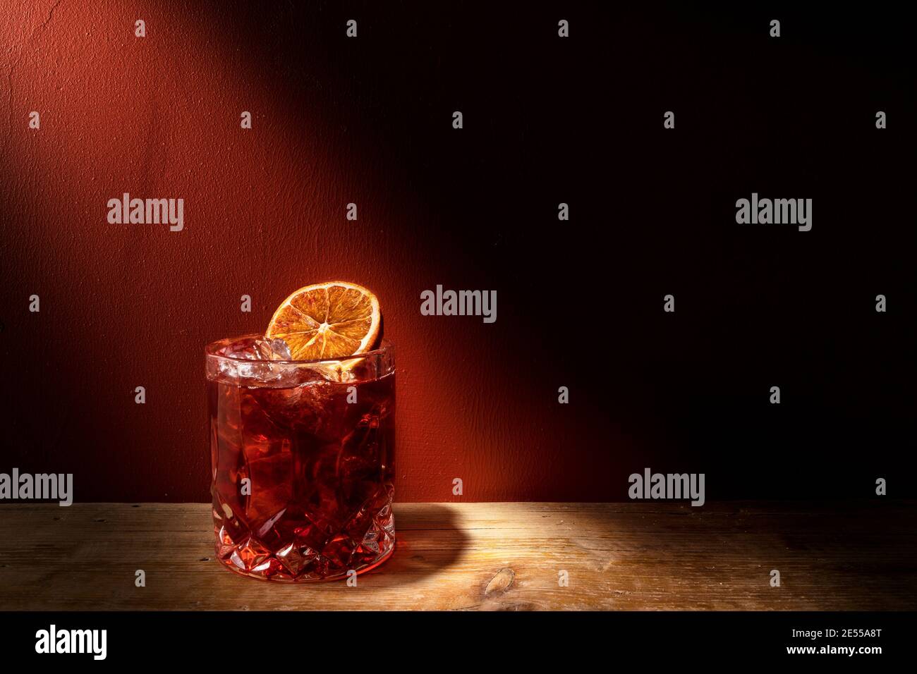 Cocktail type americano or negroni glass with ice and whole orange ...
