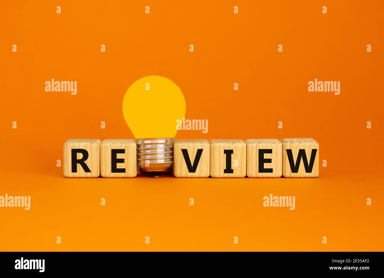 Review symbol. Wooden cubes with word 'review'. Yellow light bulb ...