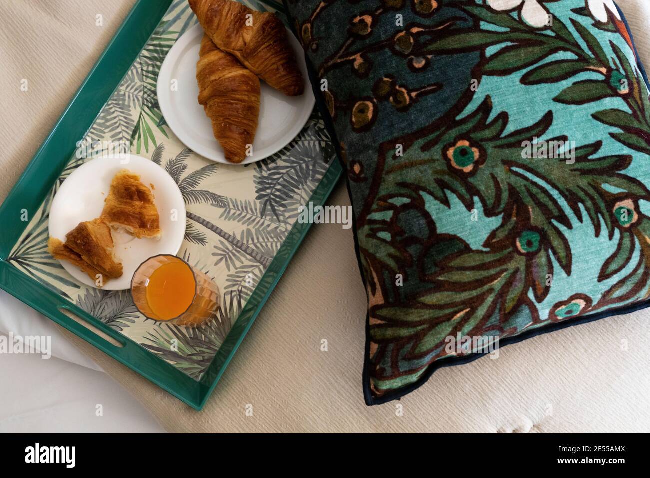 Breakfast in a hotel bedroom, tray with croissant and juice with pillow ...