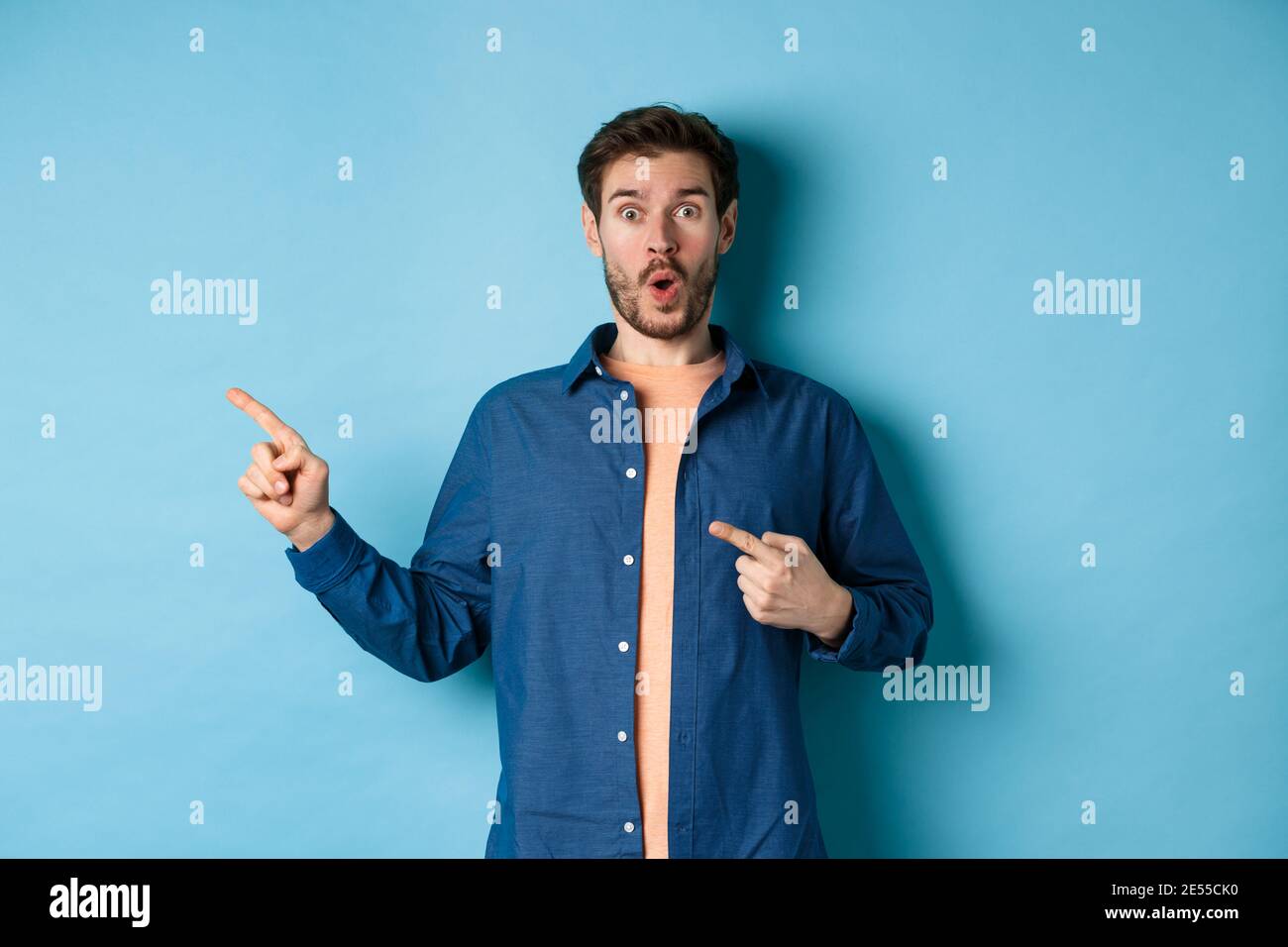 Surprised and amazed caucasian guy gasping in awe, pointing fingers ...