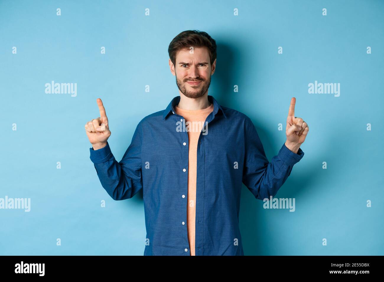 Skeptical young man frowning and squinting, cringe from something ...