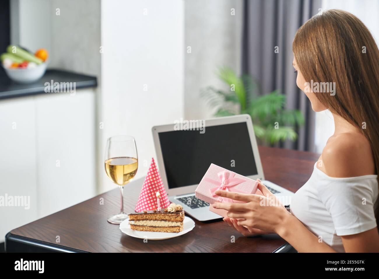 View from shoulder of young woman opening birthday present at home ...