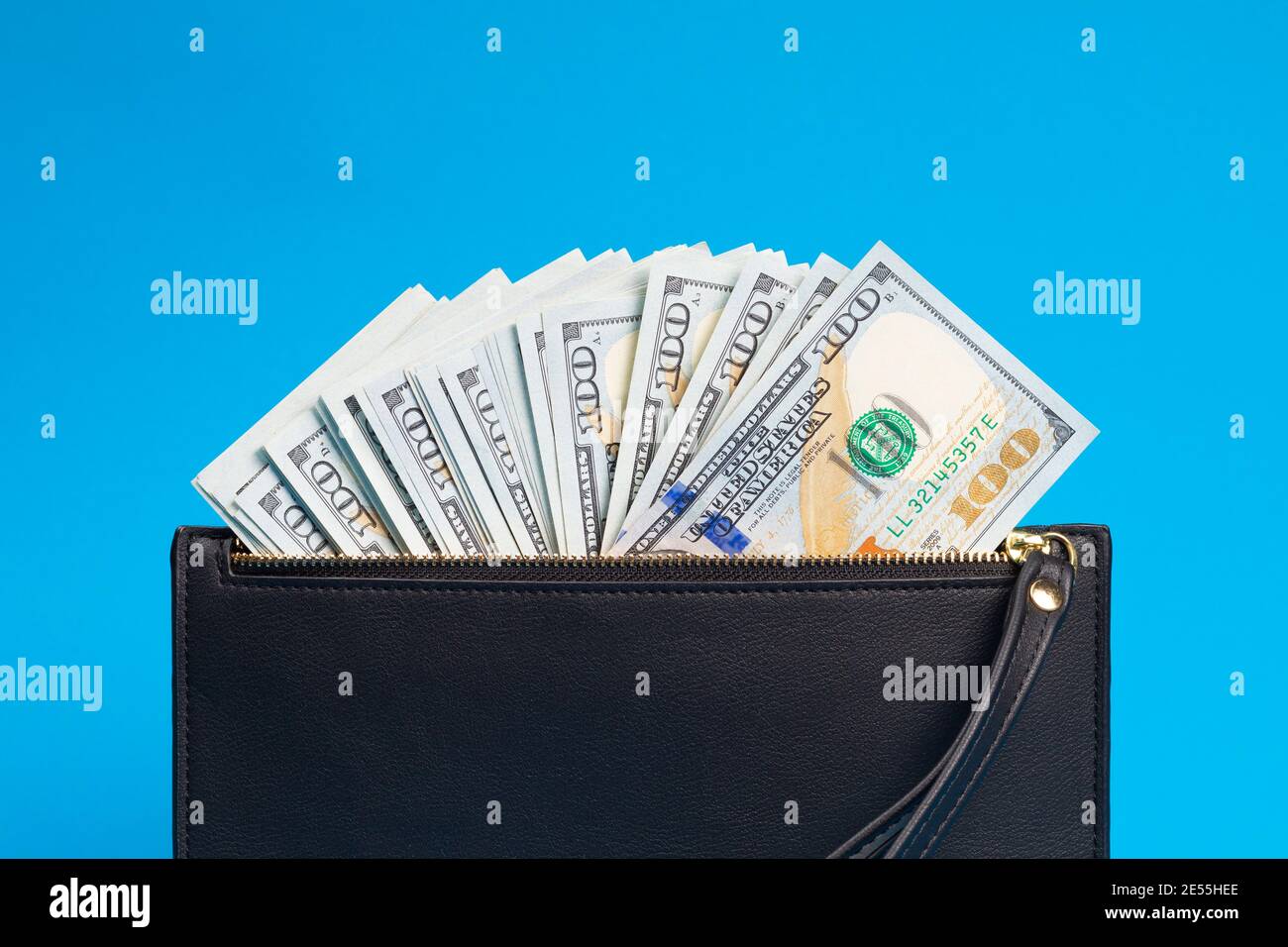 Many hundreds of dollars looks out of a black leather wallet on a blue ...