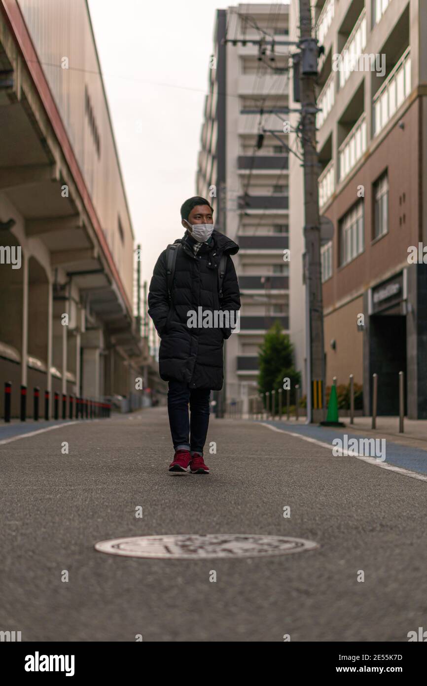 Fukuoka, Japan - January 17 2020:A man wearing jacket and mask walking ...