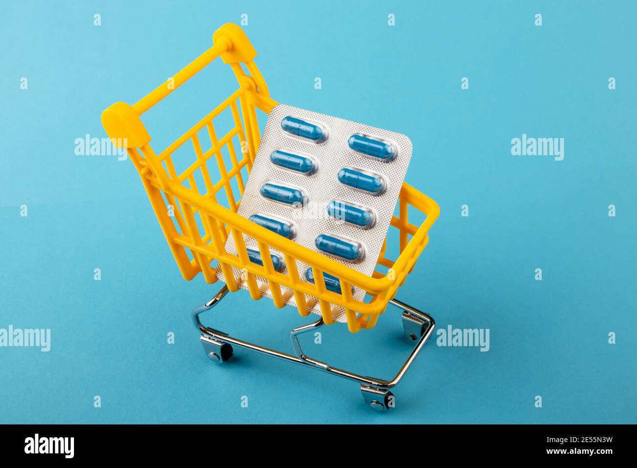 Shopping cart loaded with pills on blue background. The concept of ...