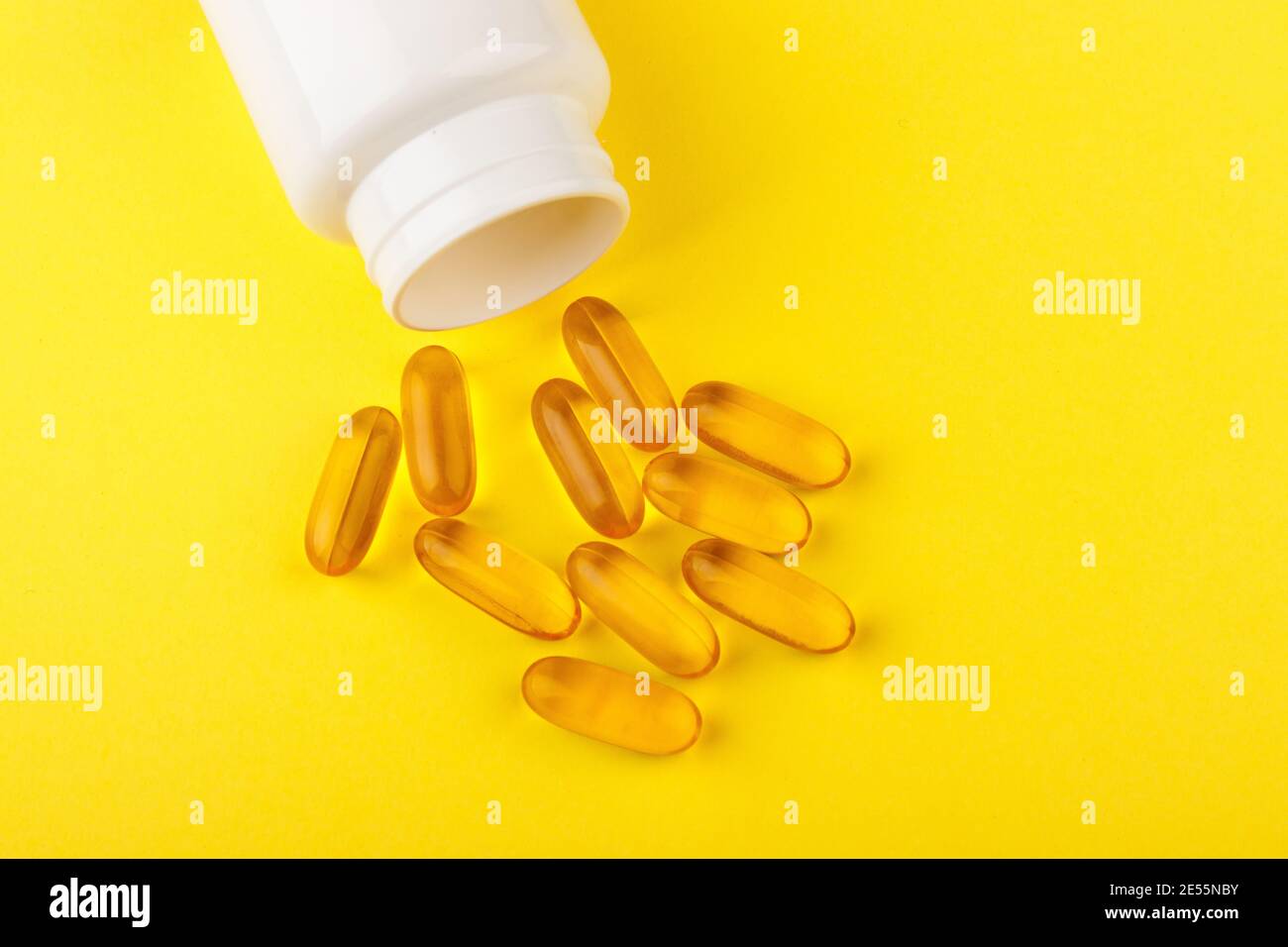 Vitamin D yellow pills on yellow background and white plastic jar ...