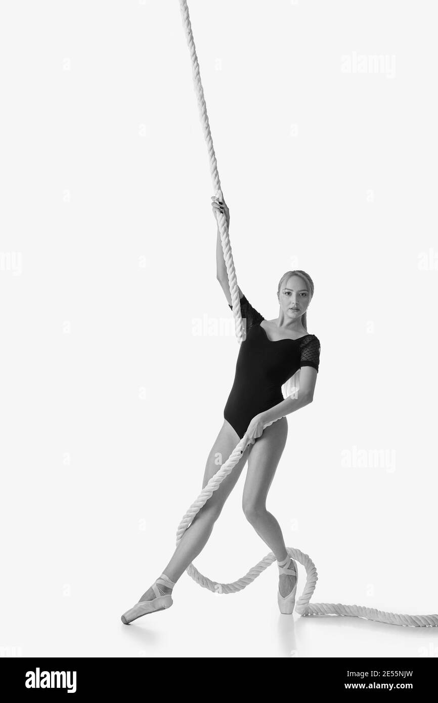 beautiful ballerina in pointe shoes is posing with rope on white studio ...