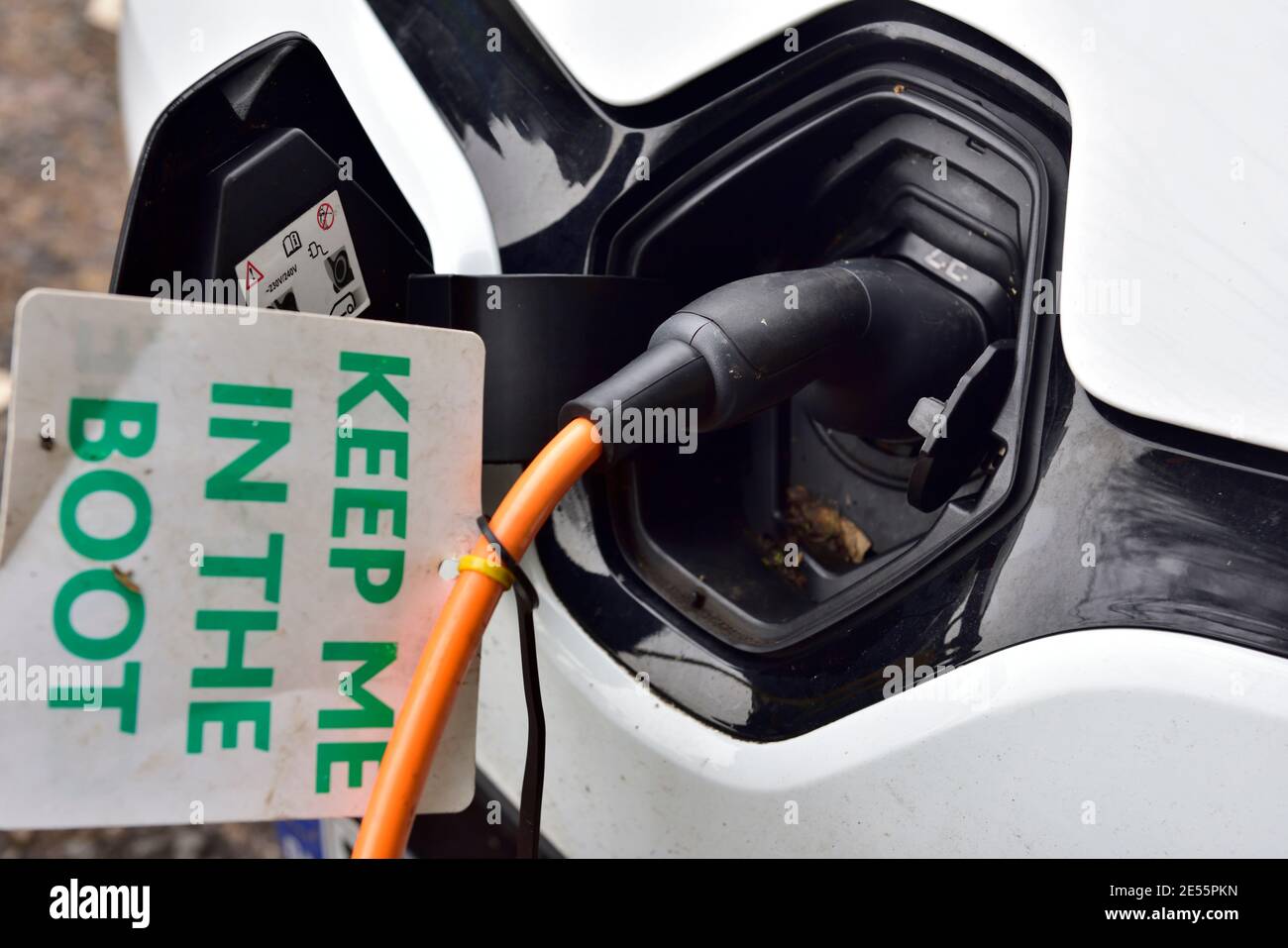 Electric car charging cable plugged into car with a note to say keep ...