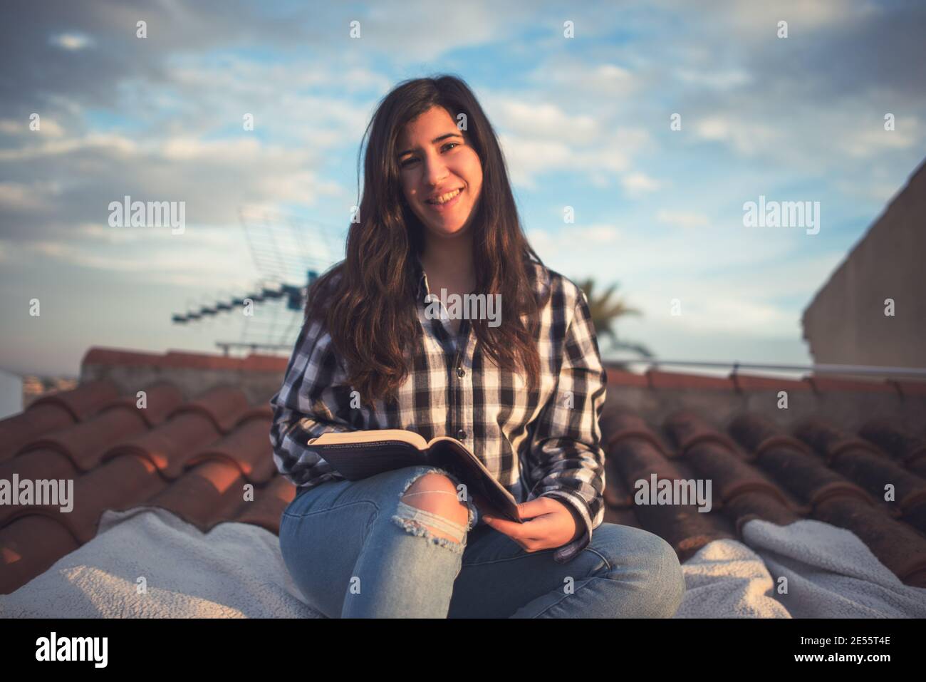 Woman in a moment of relaxation reading on the roof of her house Stock ...