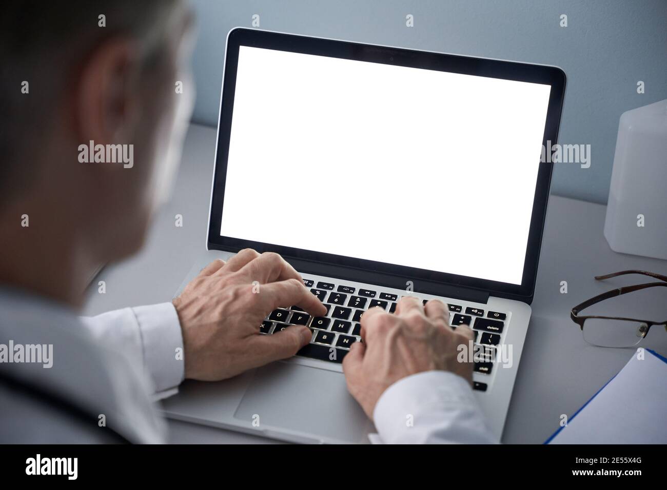 Male doctor using laptop computer with blank white mockup screen ...