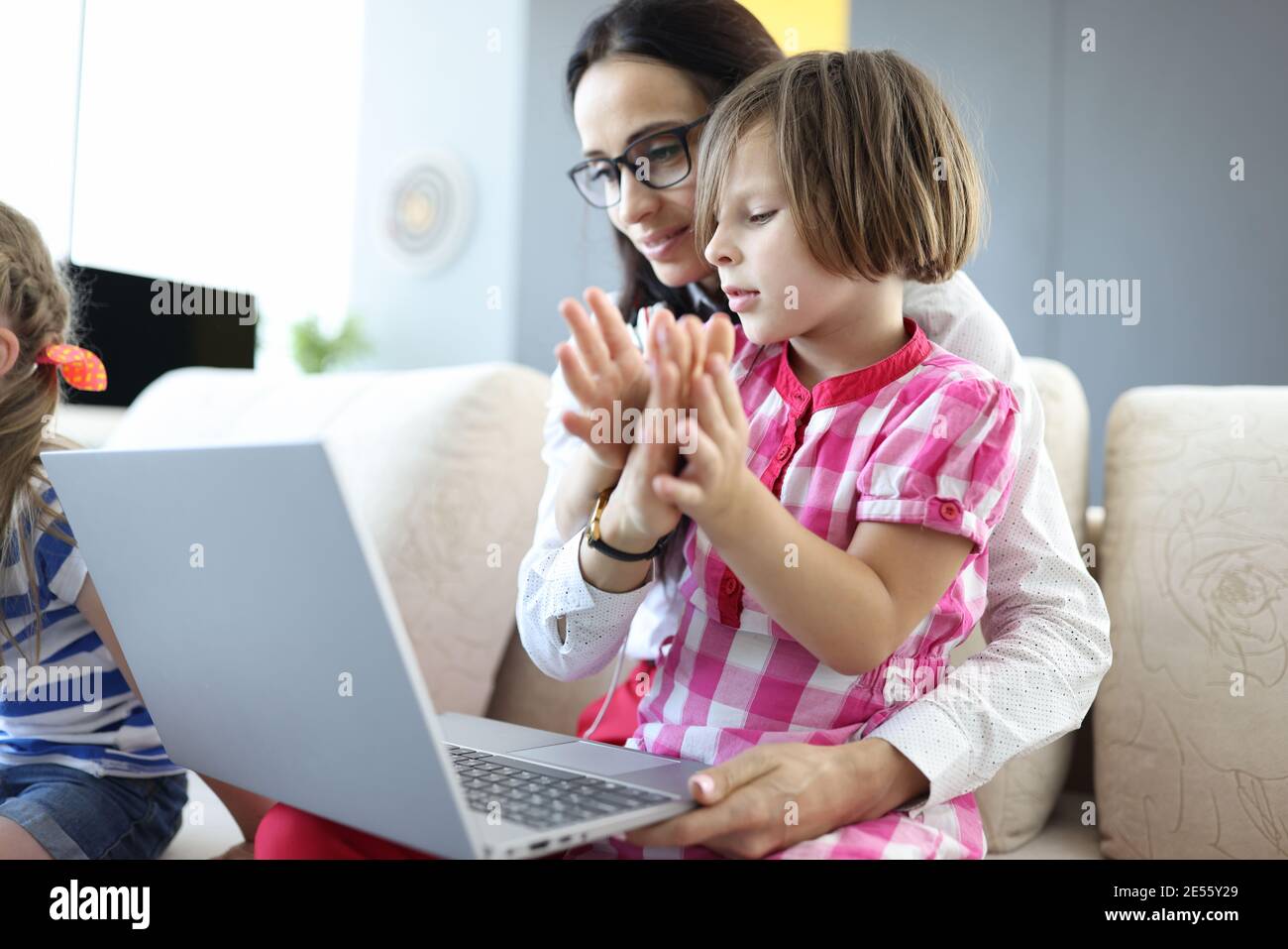 Woman holds laptop on lap of little girl sitting Stock Photo - Alamy