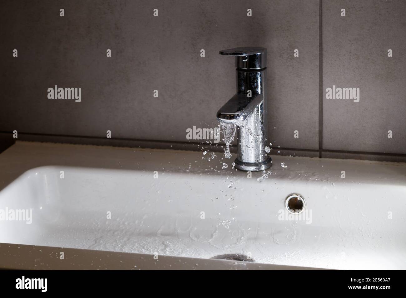 Broken water faucet in the bathroom sink. Water splashes from the ...