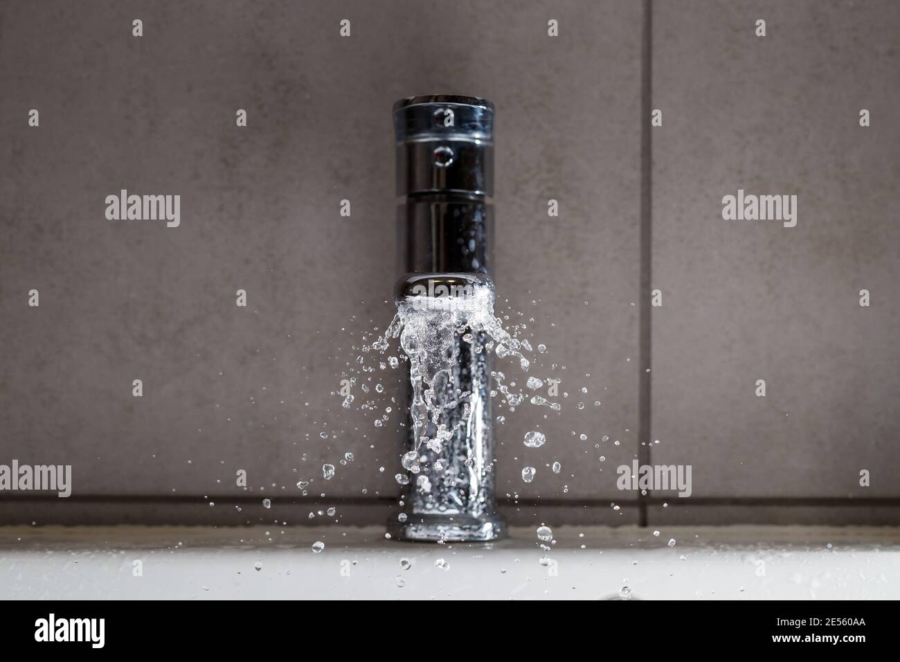 Broken water faucet in the bathroom sink. Water splashes from the ...