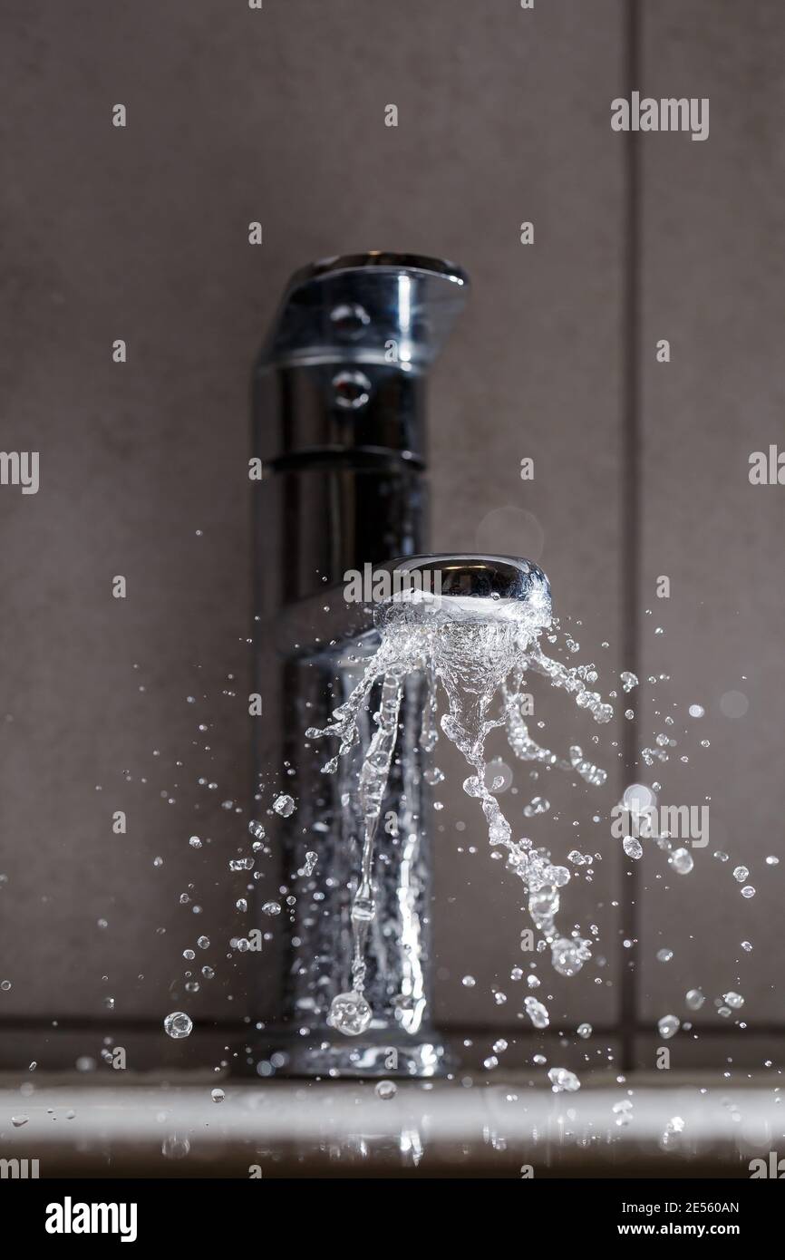 Broken water faucet in the bathroom sink. Water splashes from the ...