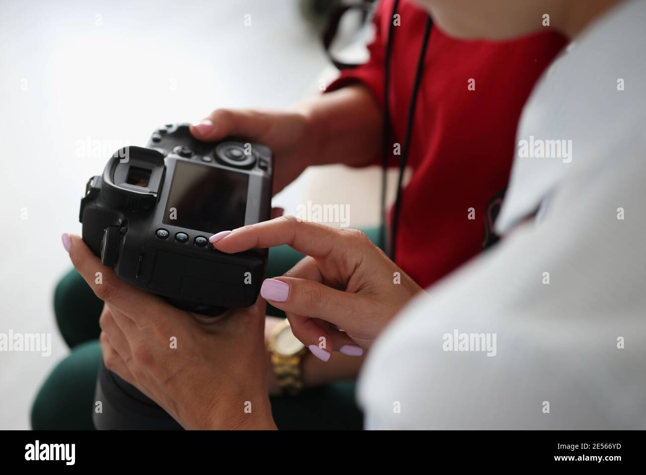 Two women hold camera in their hands Stock Photo - Alamy