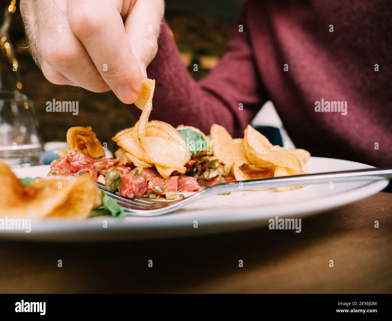 Close-up image of male hand eating from the plate potatoes chips with ...