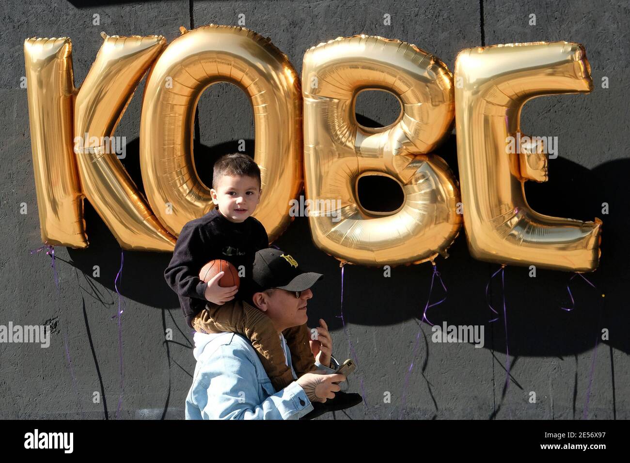 Los Angeles, California, USA. 26th Jan, 2021. A man carrying a kid with ...