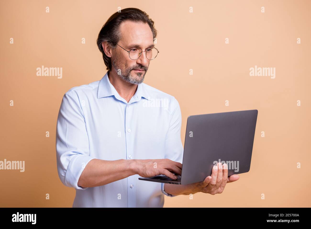 Photo of serious programmer man hold netbook look screen wear ...