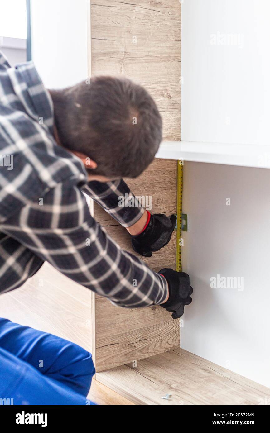Carpenter measuring shelves in an empty apartment, where he started ...