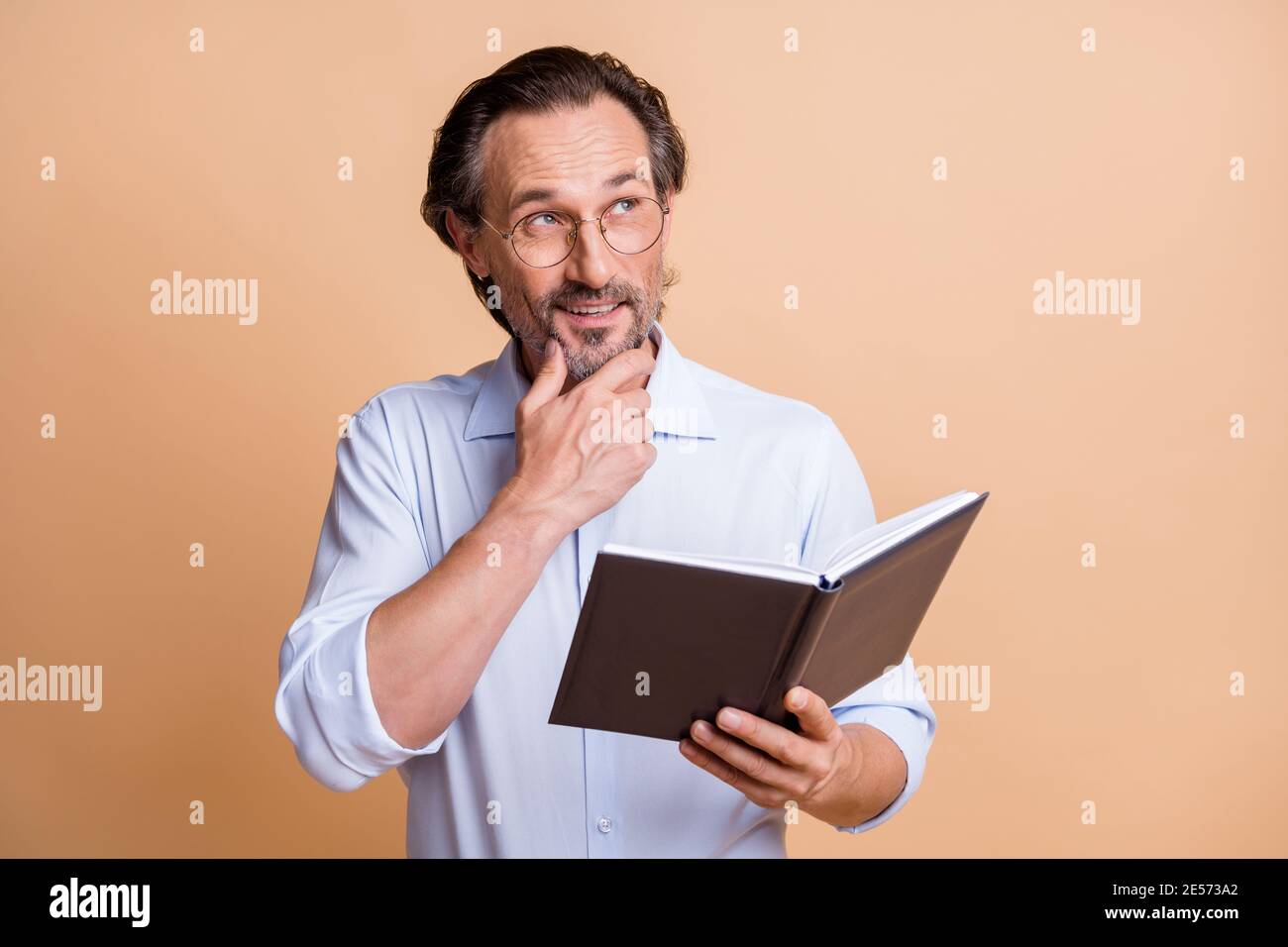 Portrait of nice creative cheerful smart man wearing specs reading book ...