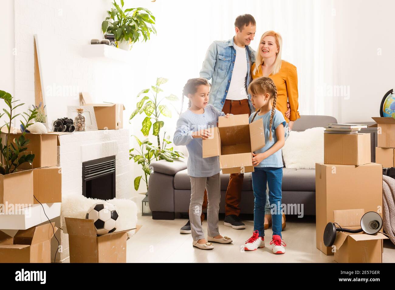 Happy family moving home with boxes around Stock Photo - Alamy