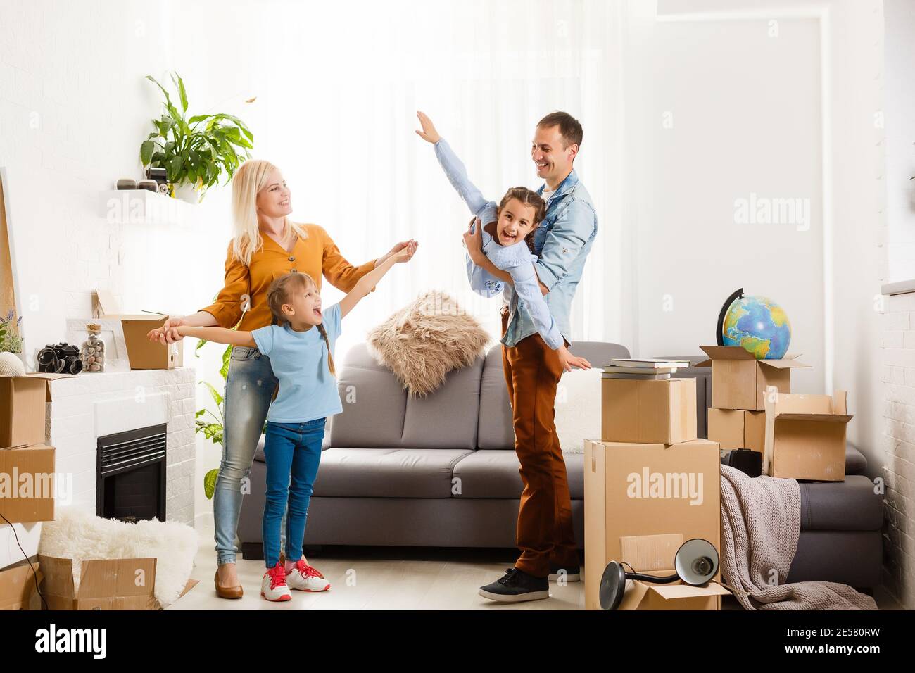 Happy family moving home with boxes around Stock Photo - Alamy
