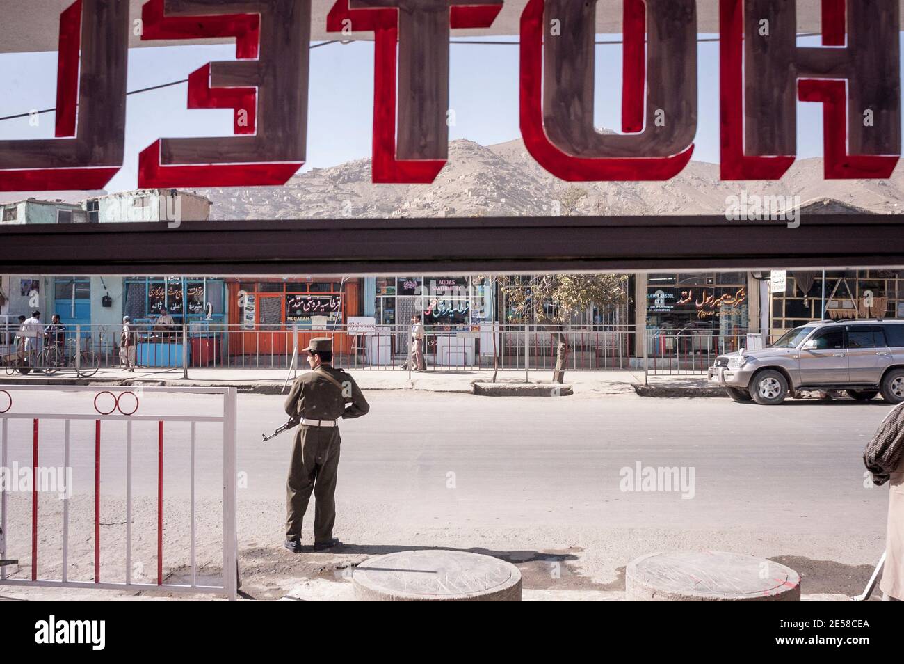 An armed security guard stands outside a hotel watching the street in ...