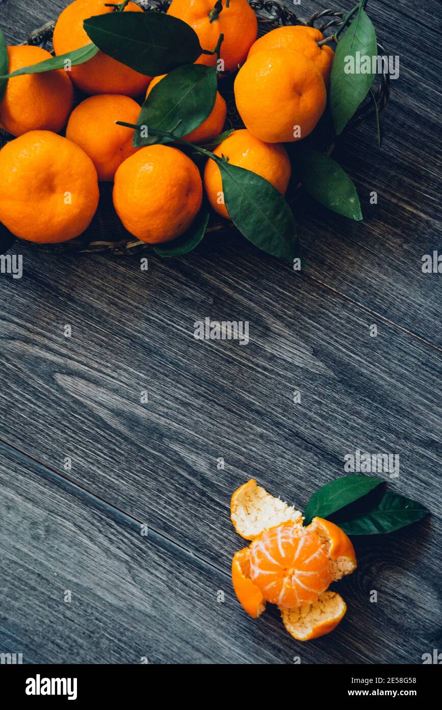 Ripe Mandarin fruit peeled open and place on old rustic look timber ...