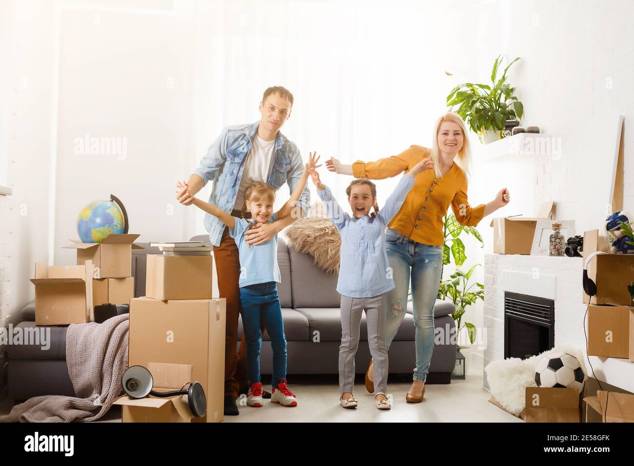 Happy family moving home with boxes around Stock Photo - Alamy