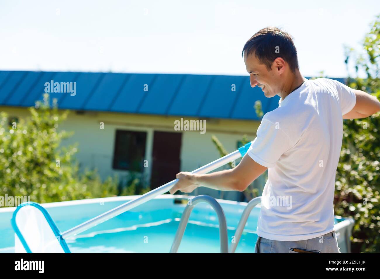 man cleaning the pool at her country house. Summer at home concept ...